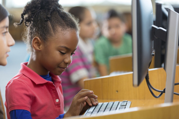 Adorable African American elementary student using computer in class ...